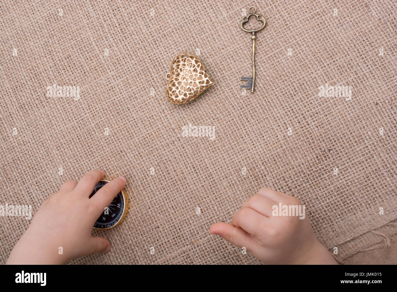 Compass, key and a heart shaped object beside a hand Stock Photo - Alamy