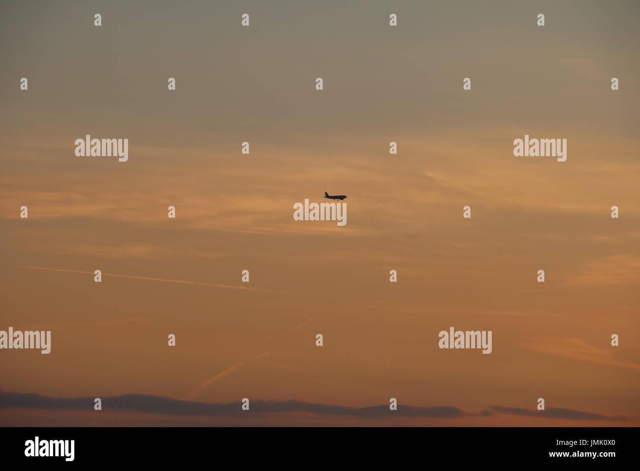 Airplane flying across the sky during sunset in Venice, Italy Stock ...