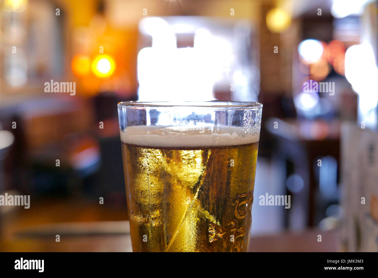Glass of lager beer sat on bar table against light from window.Out of ...