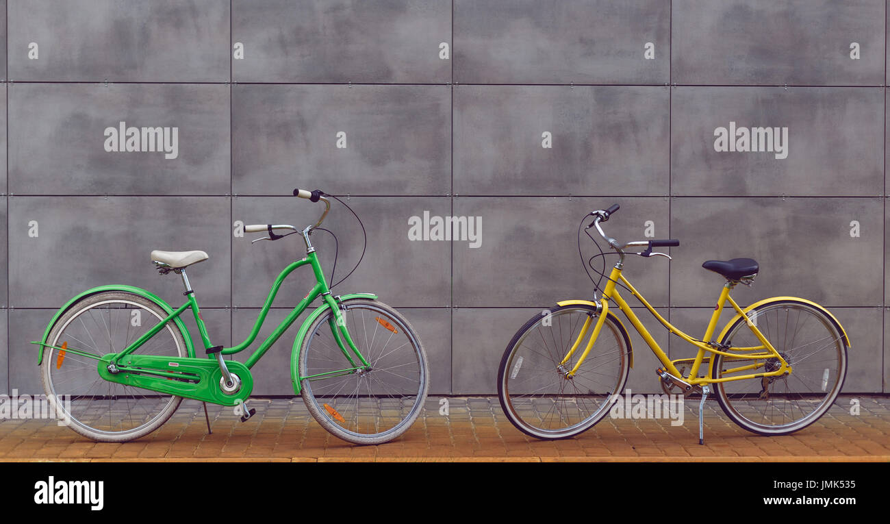 Two urban female bicycles on a gray wall background Stock Photo - Alamy