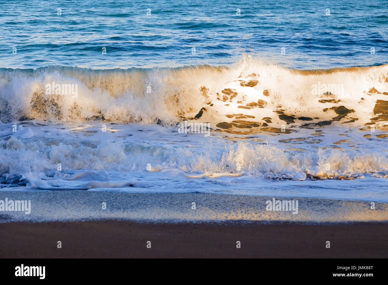 waves washing over beach shore with warm dramatic morning sun light ...