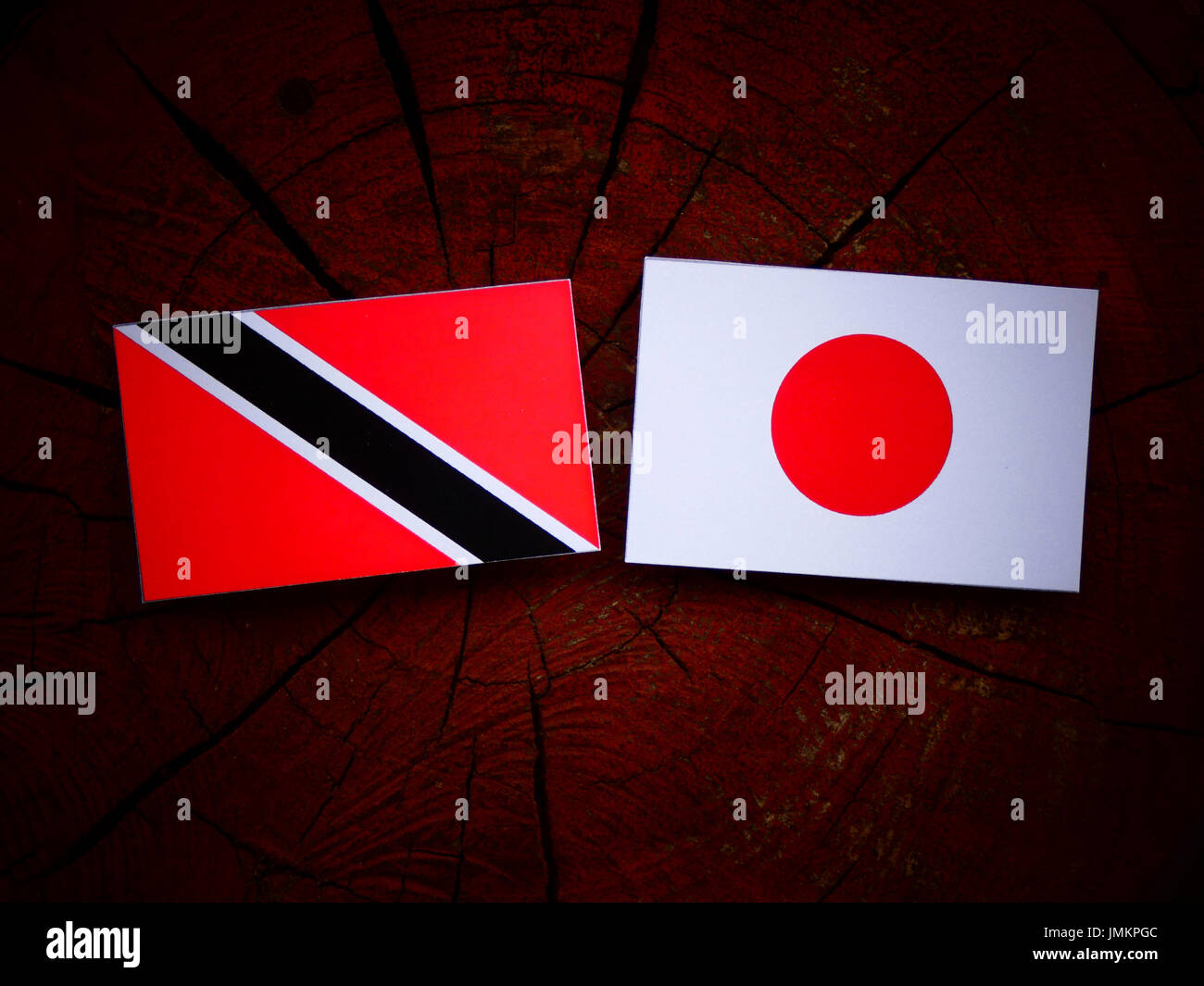 Trinidad and Tobago flag with Japanese flag on a tree stump isolated ...