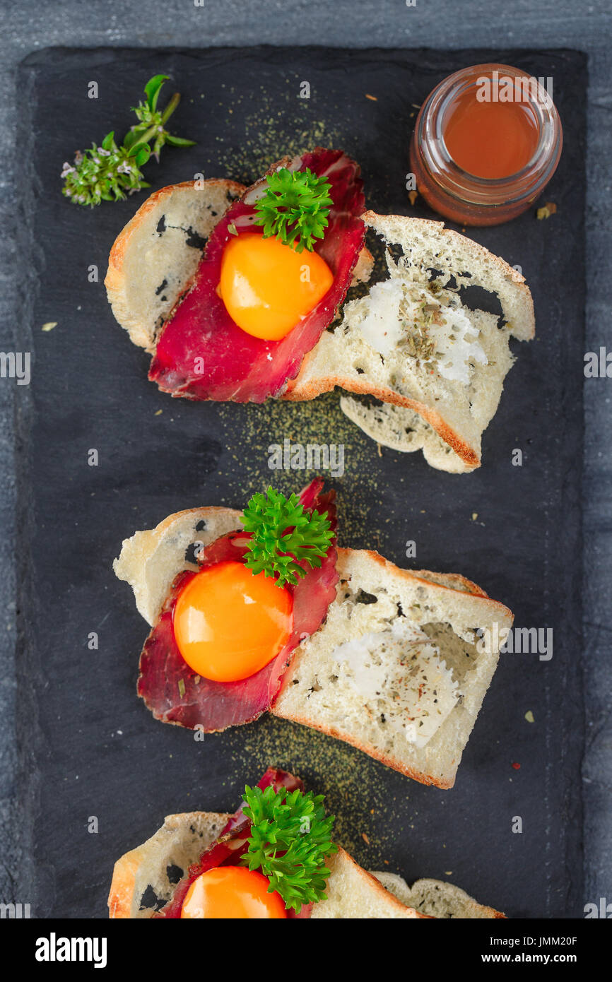 Spanish tapas with slices cured meat and yolk, close view from tiop ...