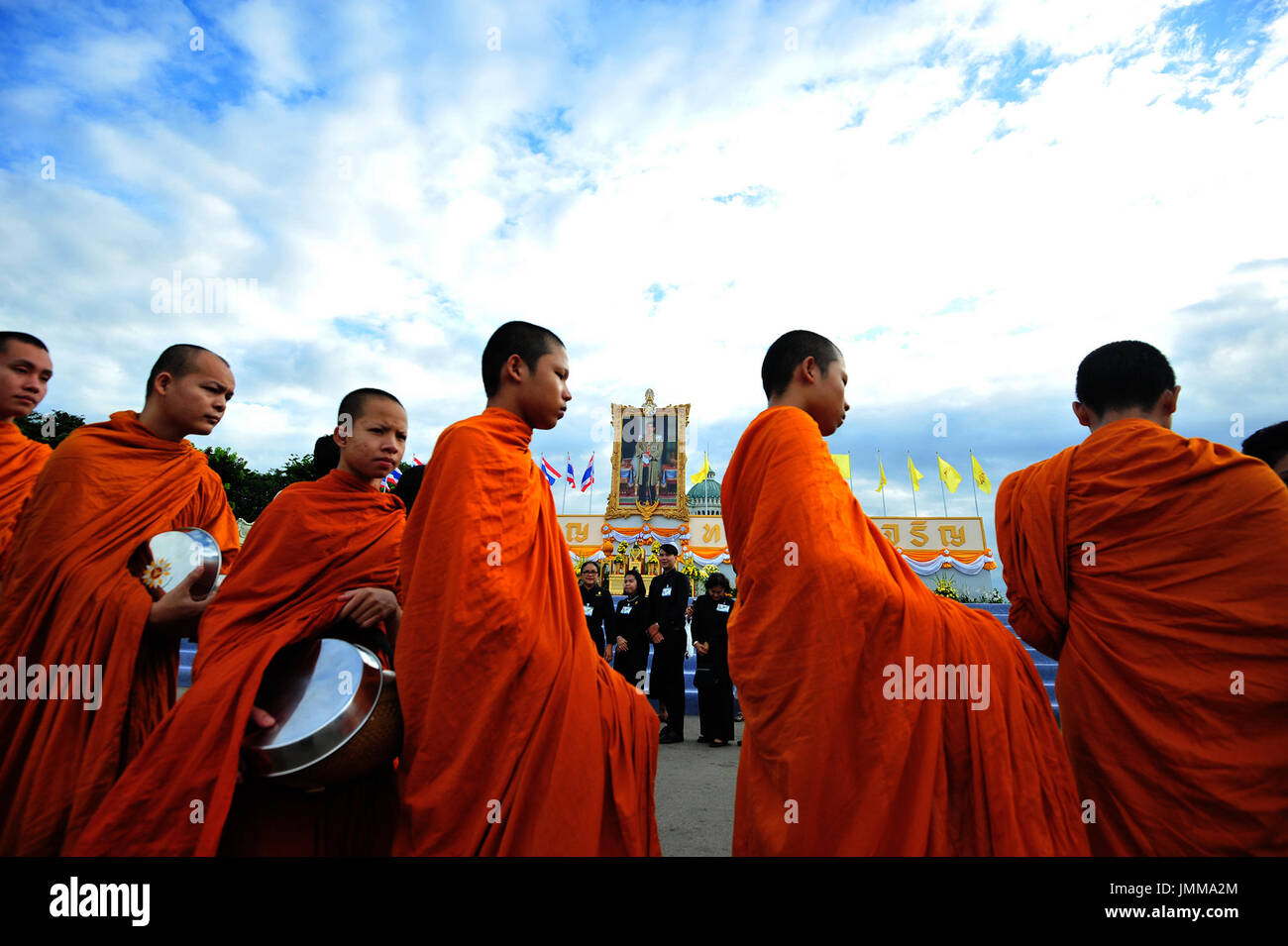 Bangkok, Thailand. 28th July, 2017. Buddhist monks walk past a portrait ...