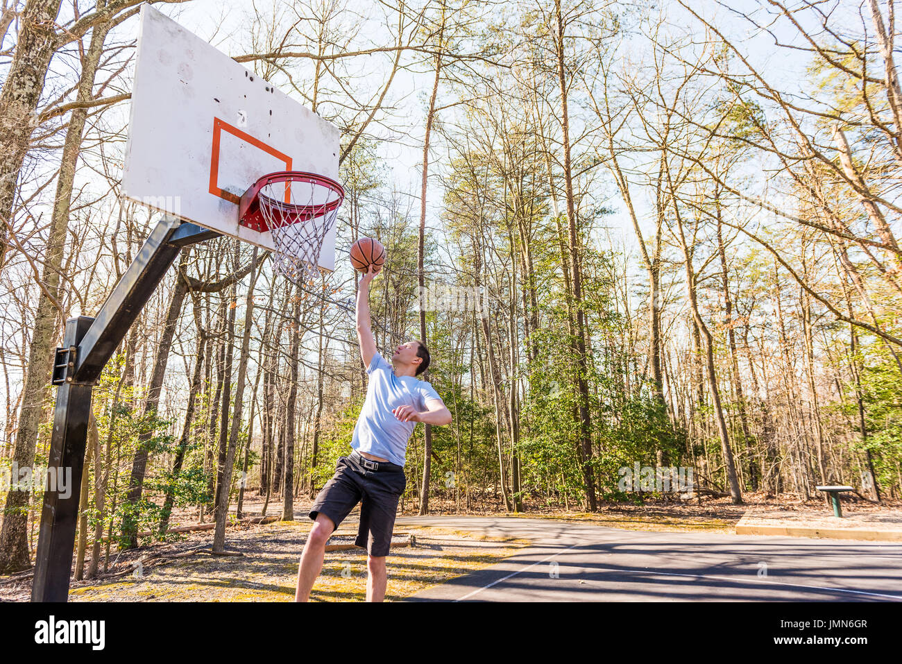 Young fit muscular man jumping up throwing basketball into hoop Stock ...