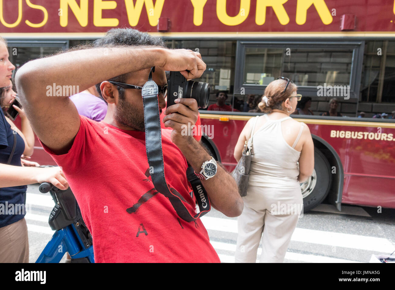 Young Indian man holding a camera to its eye / head on the street of ...