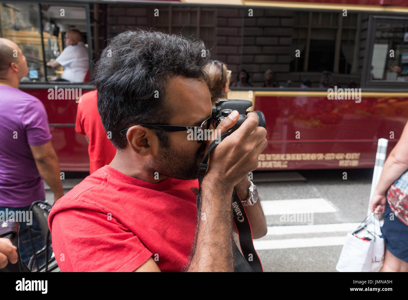 Young Indian man holding a camera to its eye / head on the street of ...