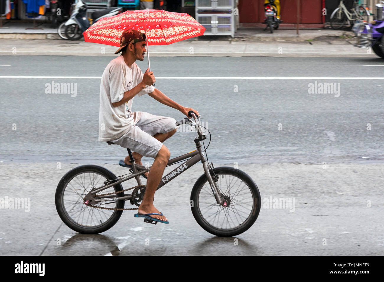 Cyclist with umbrella, Angeles City, Pampanga, Philippines Stock Photo ...