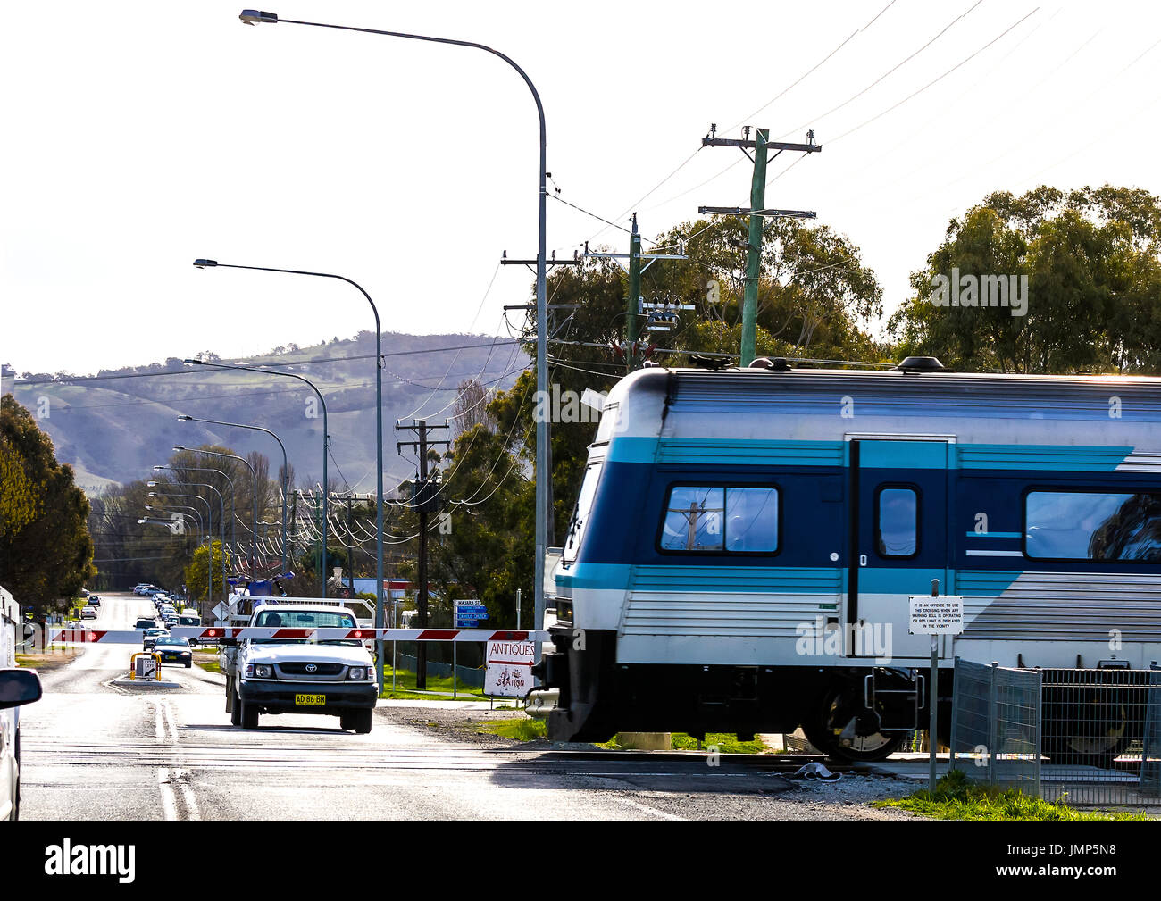 Traffic waits at level crossing for train to pass in NSW country town ...