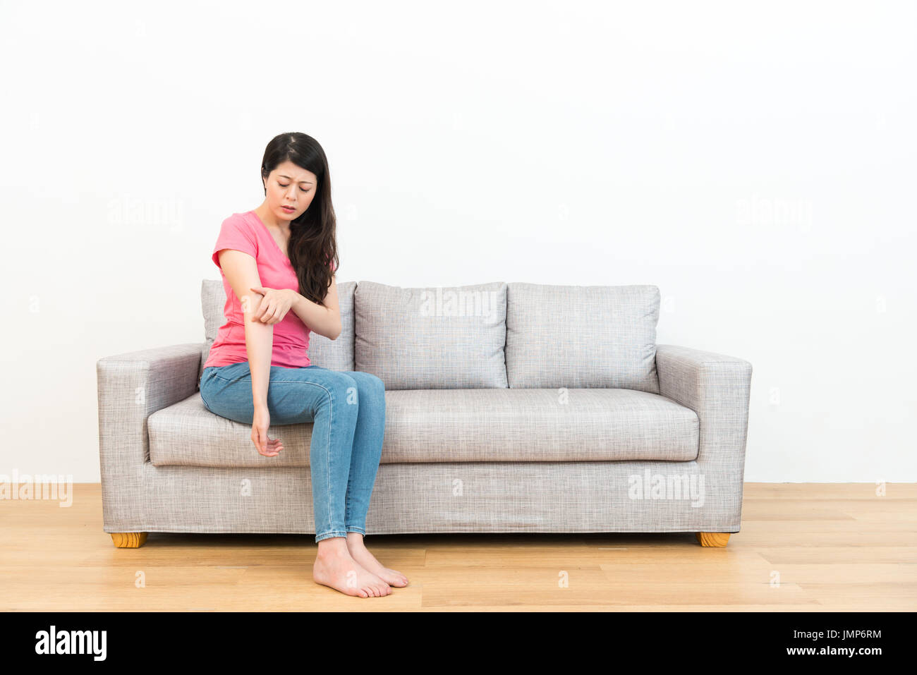 unhappy elegant lady in white background with wooden floor and her arms ...