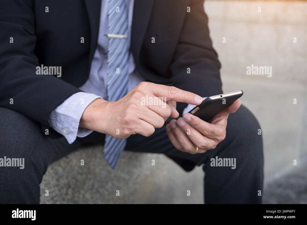 business man wearing black suit and using modern smartphone in outdoor ...