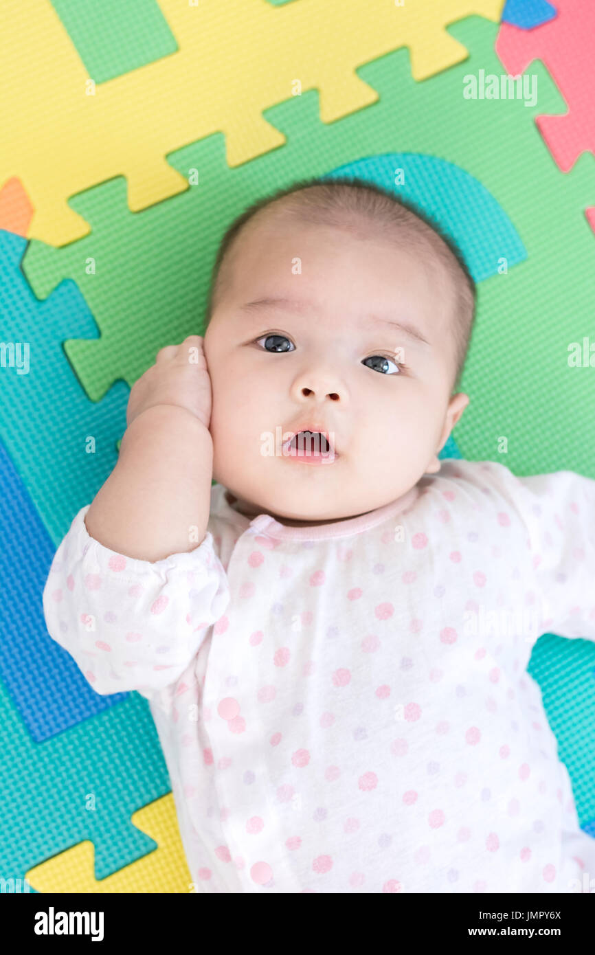 Portrait of a little adorable newborn infant baby girl lying on back on ...