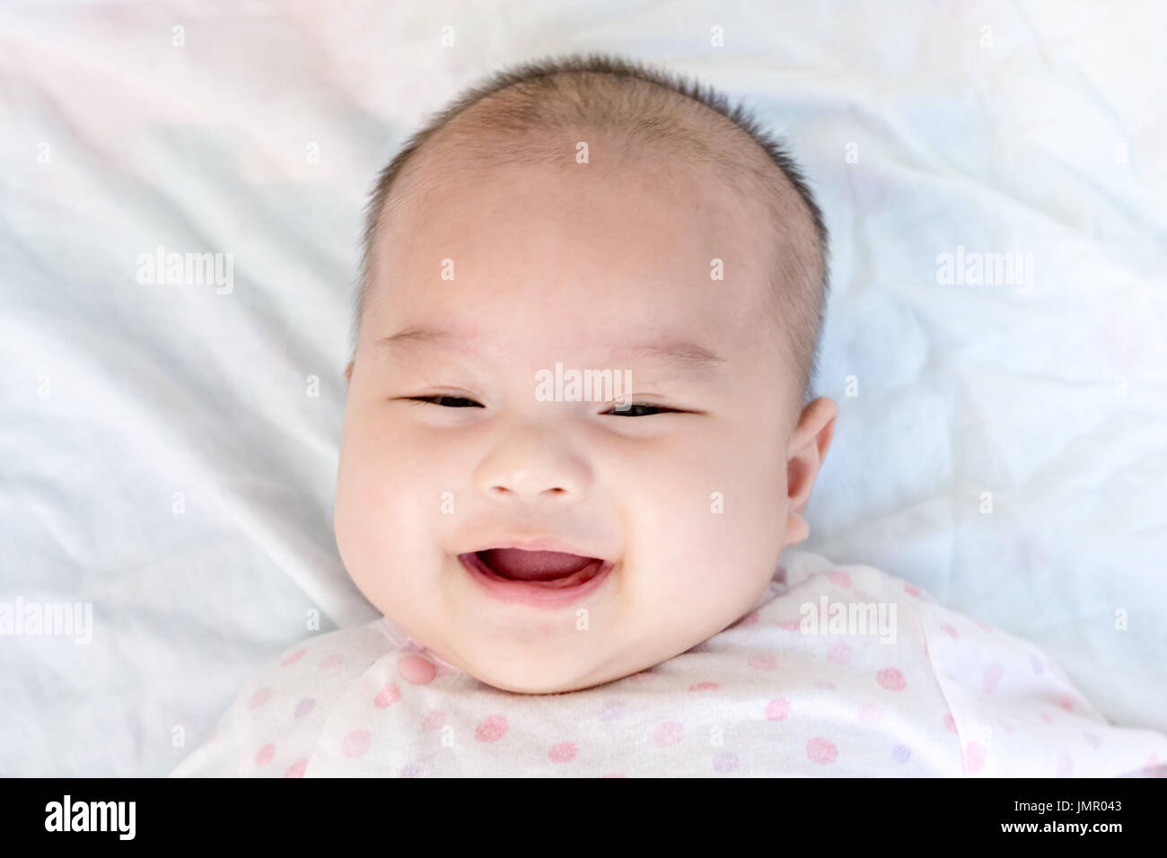 Portrait of a little adorable infant baby girl lying on back on blanket ...