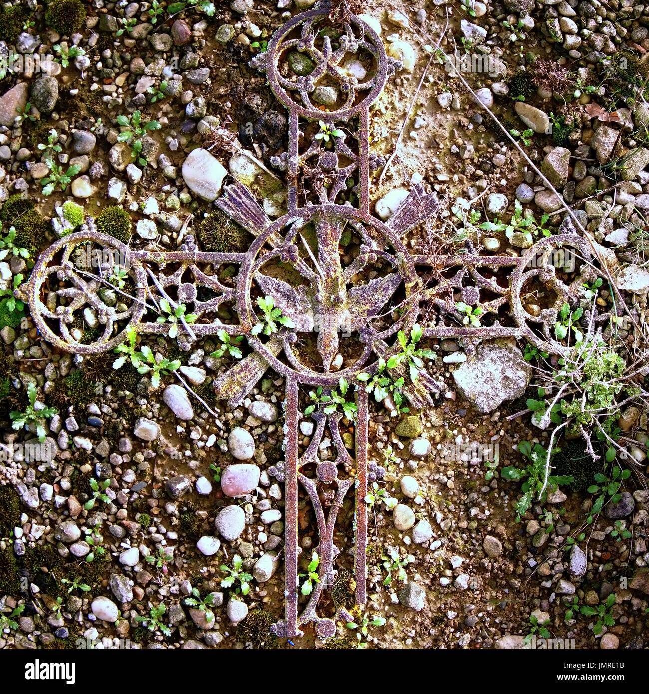 Broken iron rustic crucifix on old mossy tombstone. Abandoned symbol of ...