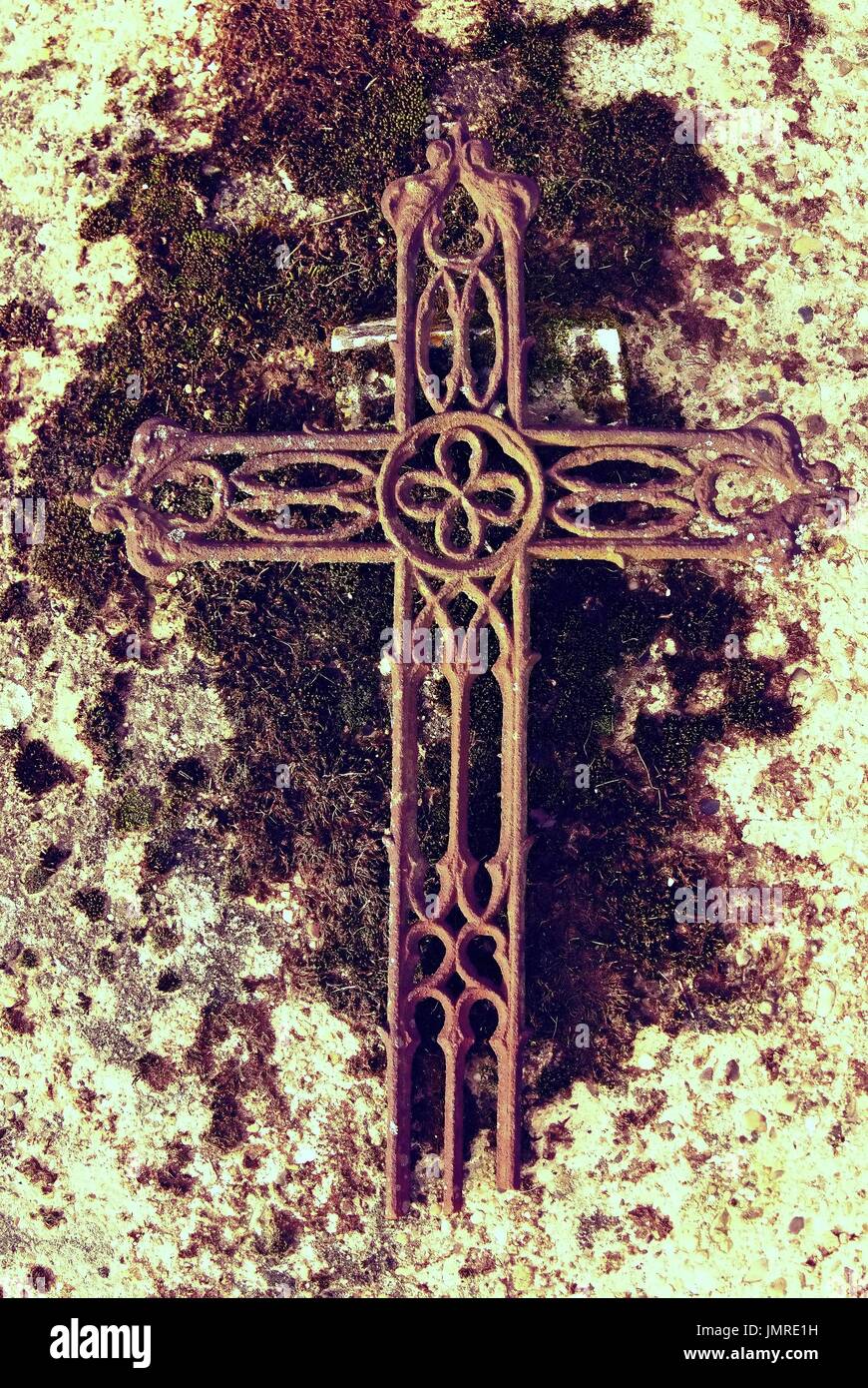 Broken iron rustic crucifix on old mossy tombstone. Abandoned symbol of ...