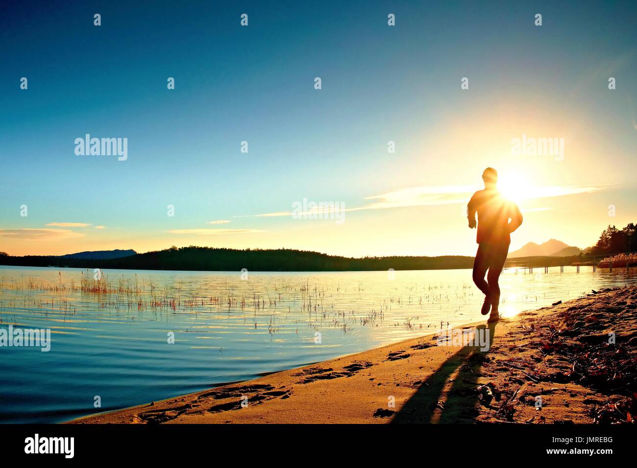 Sportsman running at amazing summer sunset along coastline in sport and ...