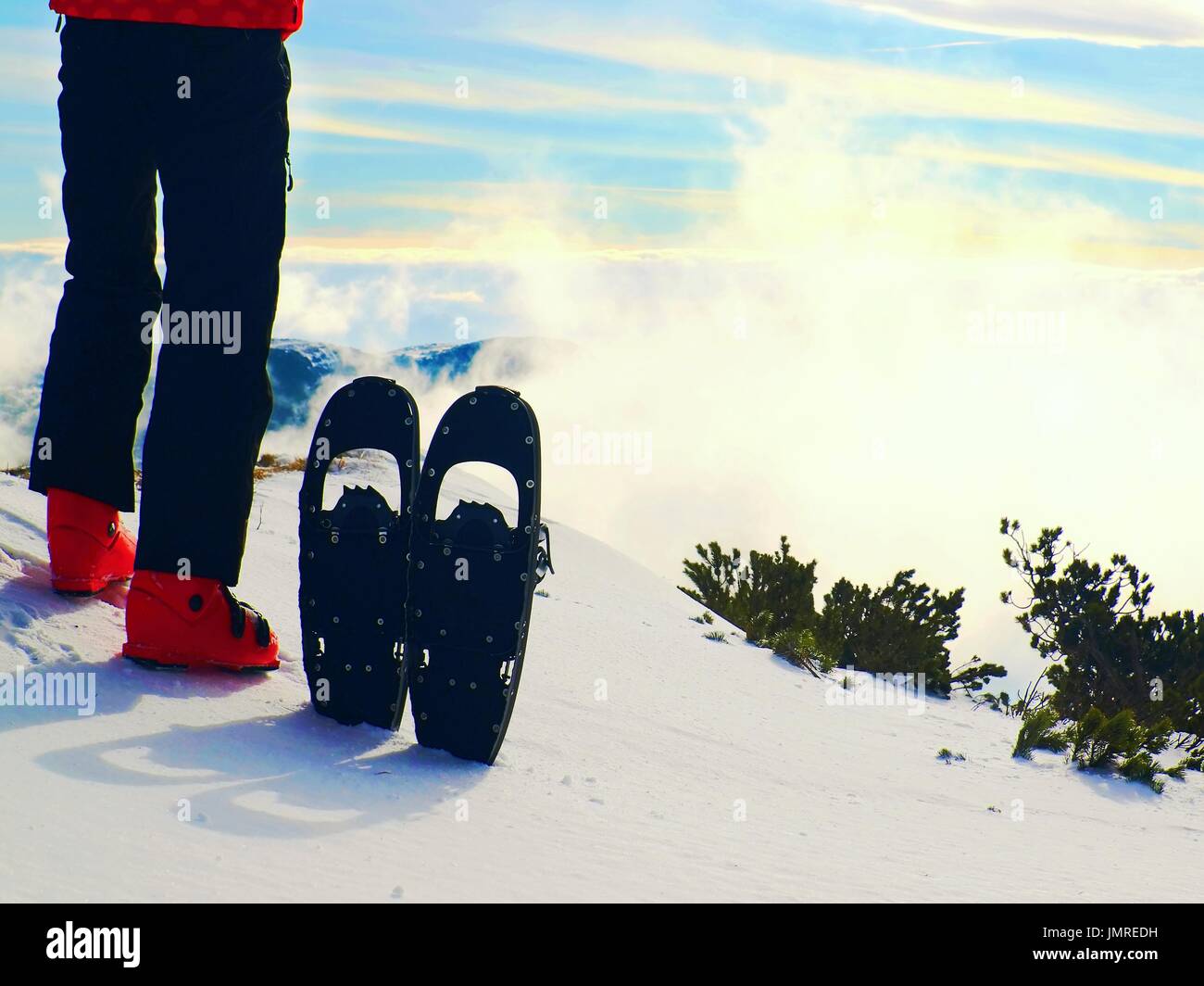 Skier in red winter jacket with fun snowshoes stay in snow in mountains ...