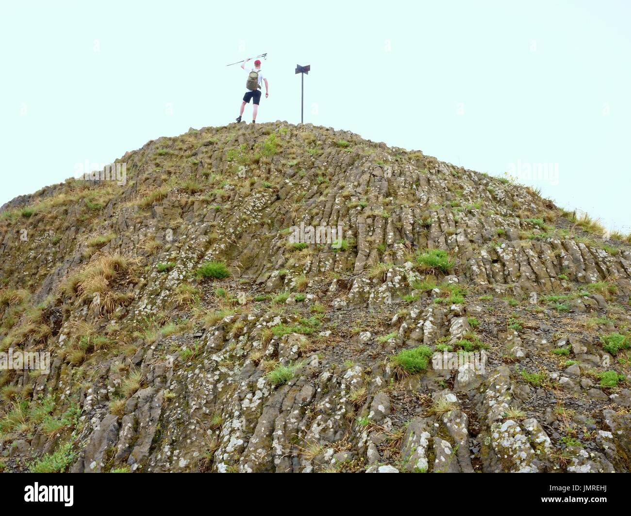 Tourist on sharp peak of basalt formation. Long basalt poles of cold ...