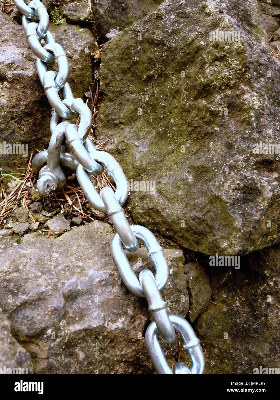Eye bolt with iron chain anchored into sandstone rock. Twisted chain of ...