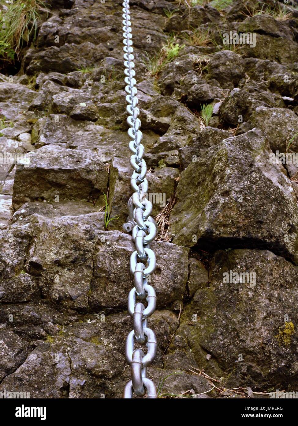 Detail of chain anchored in hard whinstone rock. Climbers path via ...