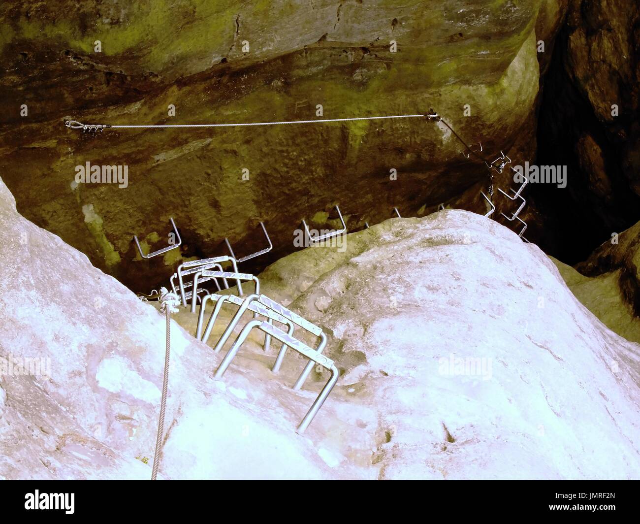 Iron cramps in rock, tourist ladder. Iron twisted rope fixed in block ...