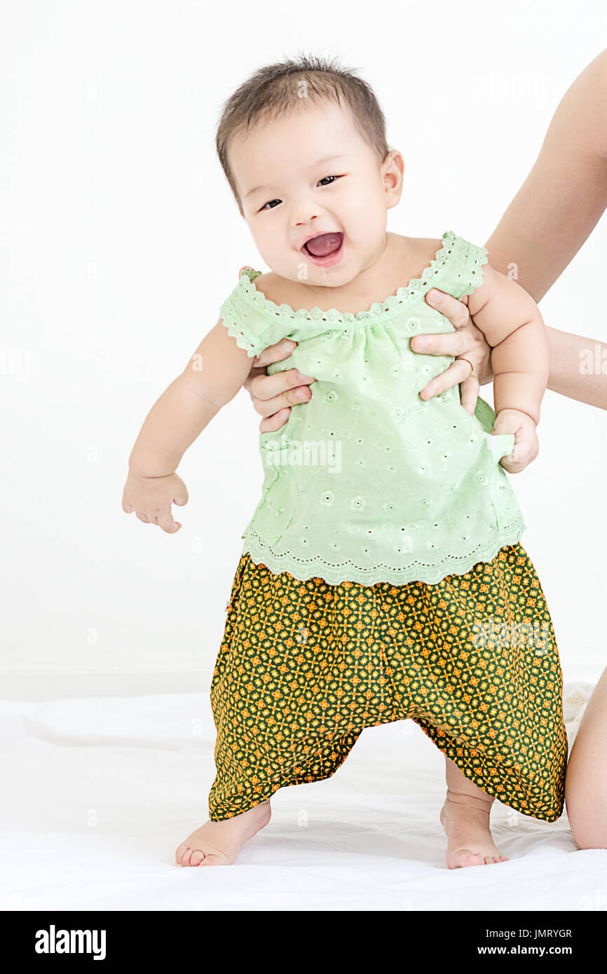Adorable infant baby girl learning to walk with mother help at home ...