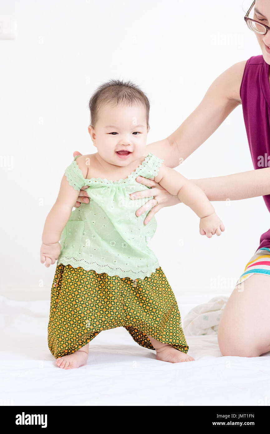 Adorable infant baby girl learning to walk with mother help at home ...