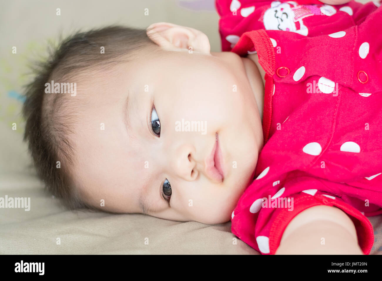 Portrait of a little adorable infant baby girl lying on back on the bed ...