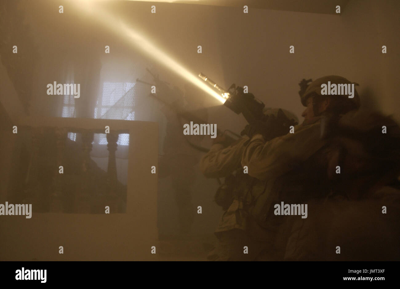 The beam of a flashlight fastened to a rifle cuts through the dust in ...