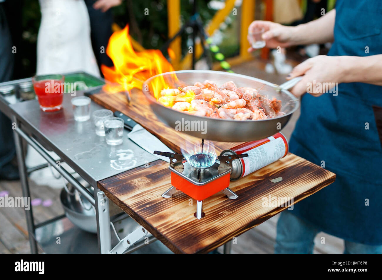 Flambe. Fried king prawns on iron pan. chief cook pours the alcohol and ...