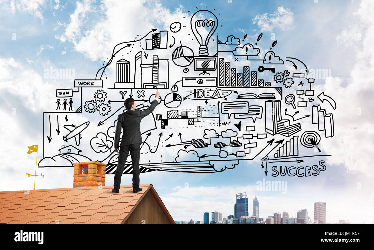Rear view of businessman on house roof drawing his new business ...