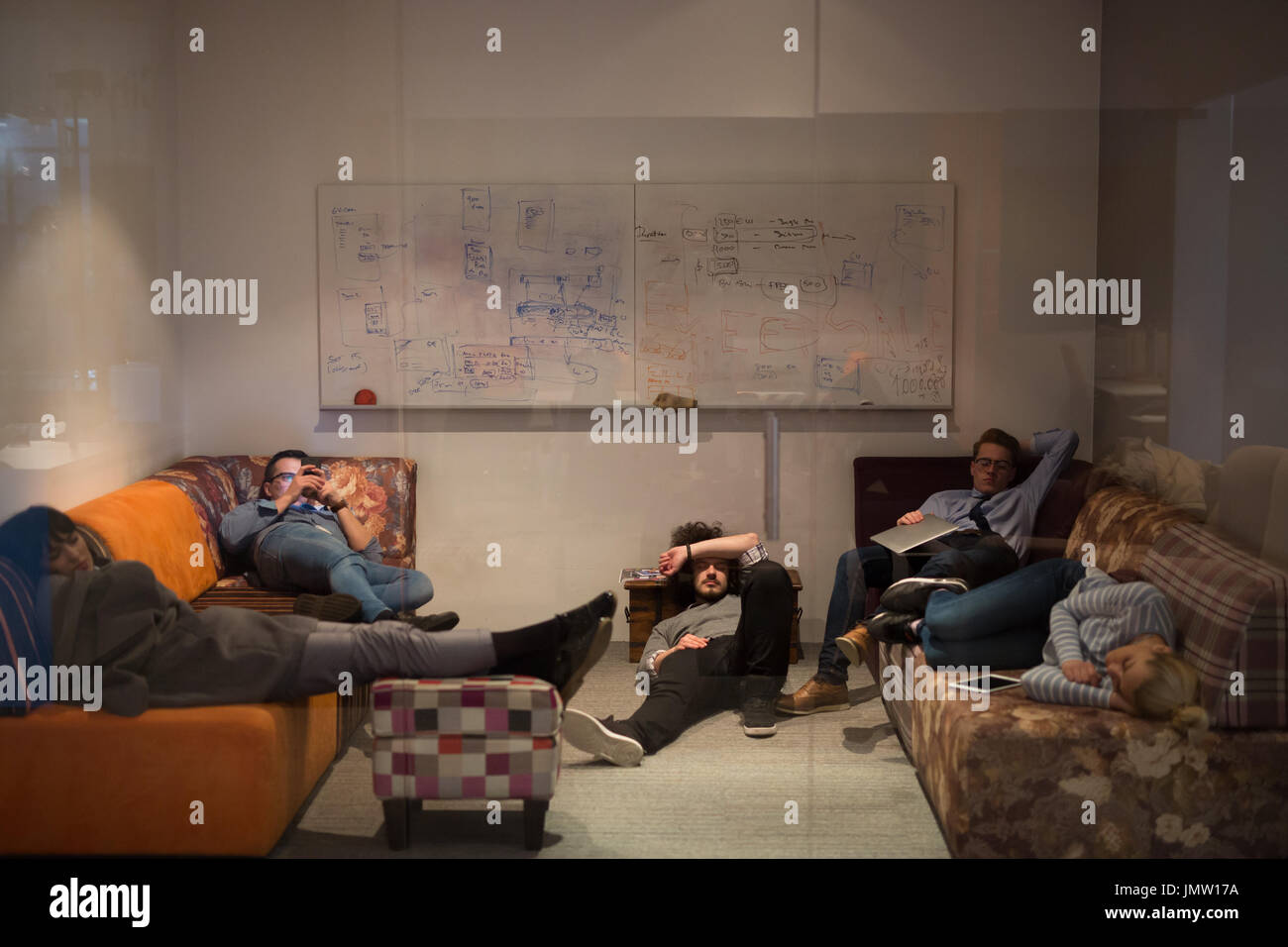 group of young casual software developer sleeping on sofa during a work ...