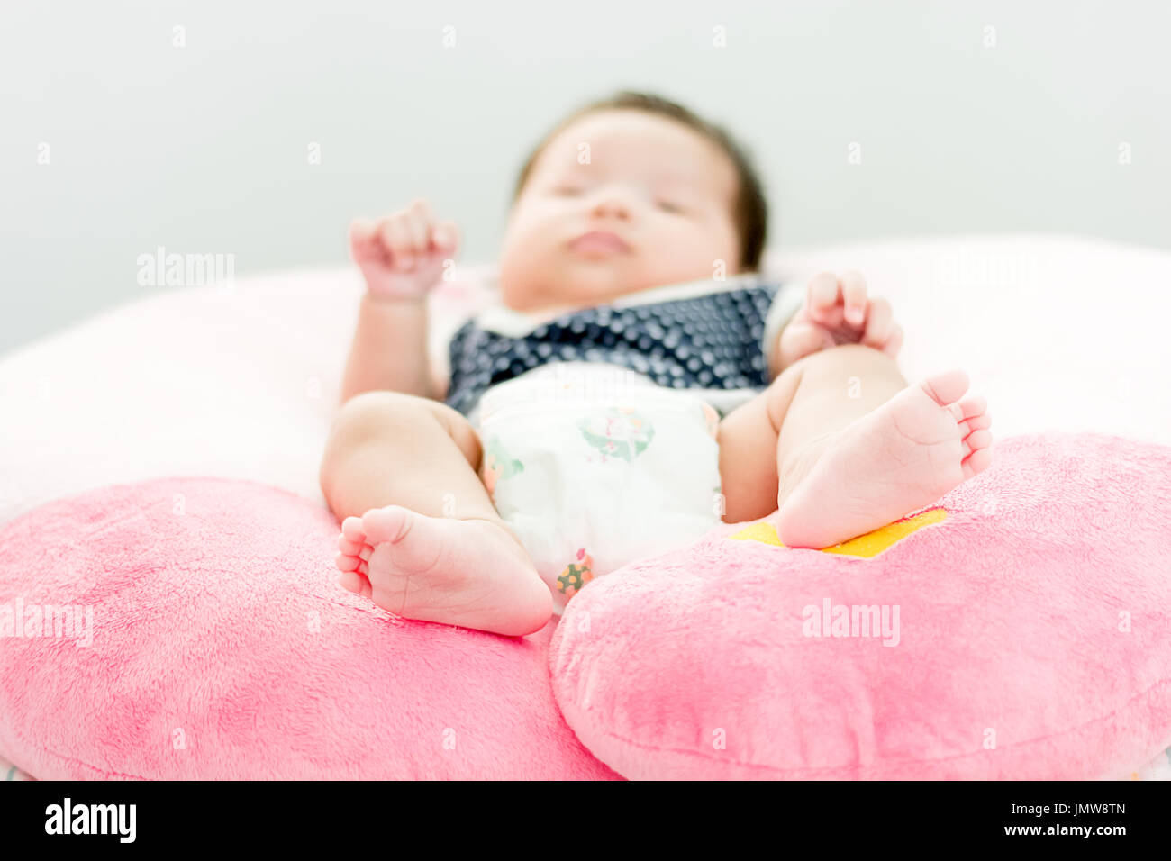 Portrait of a little adorable infant baby girl's feet lying on back ...