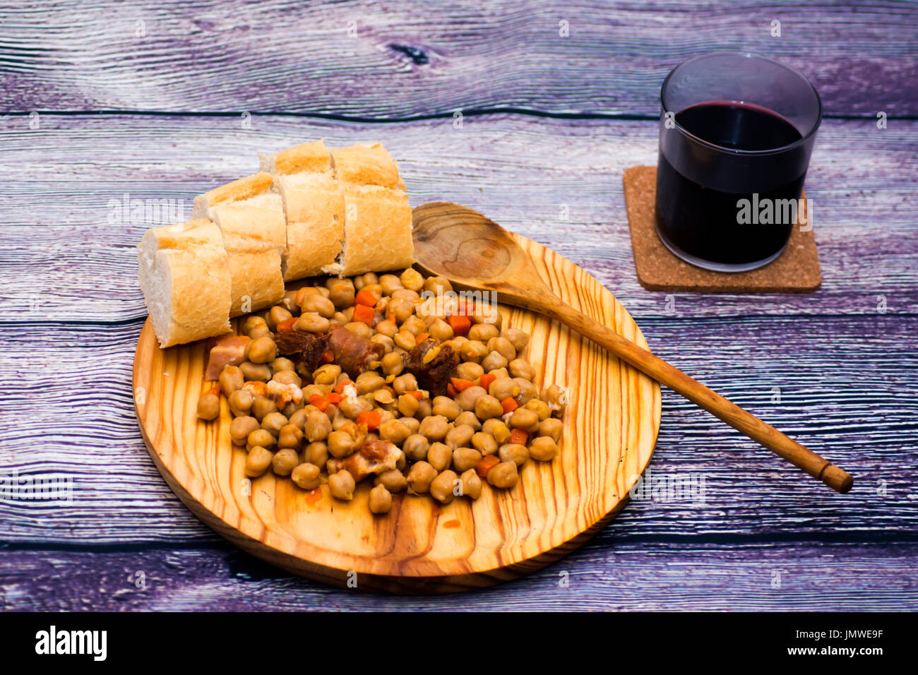 Madrid stew on a plate on a wooden table With bread and a glass of red ...