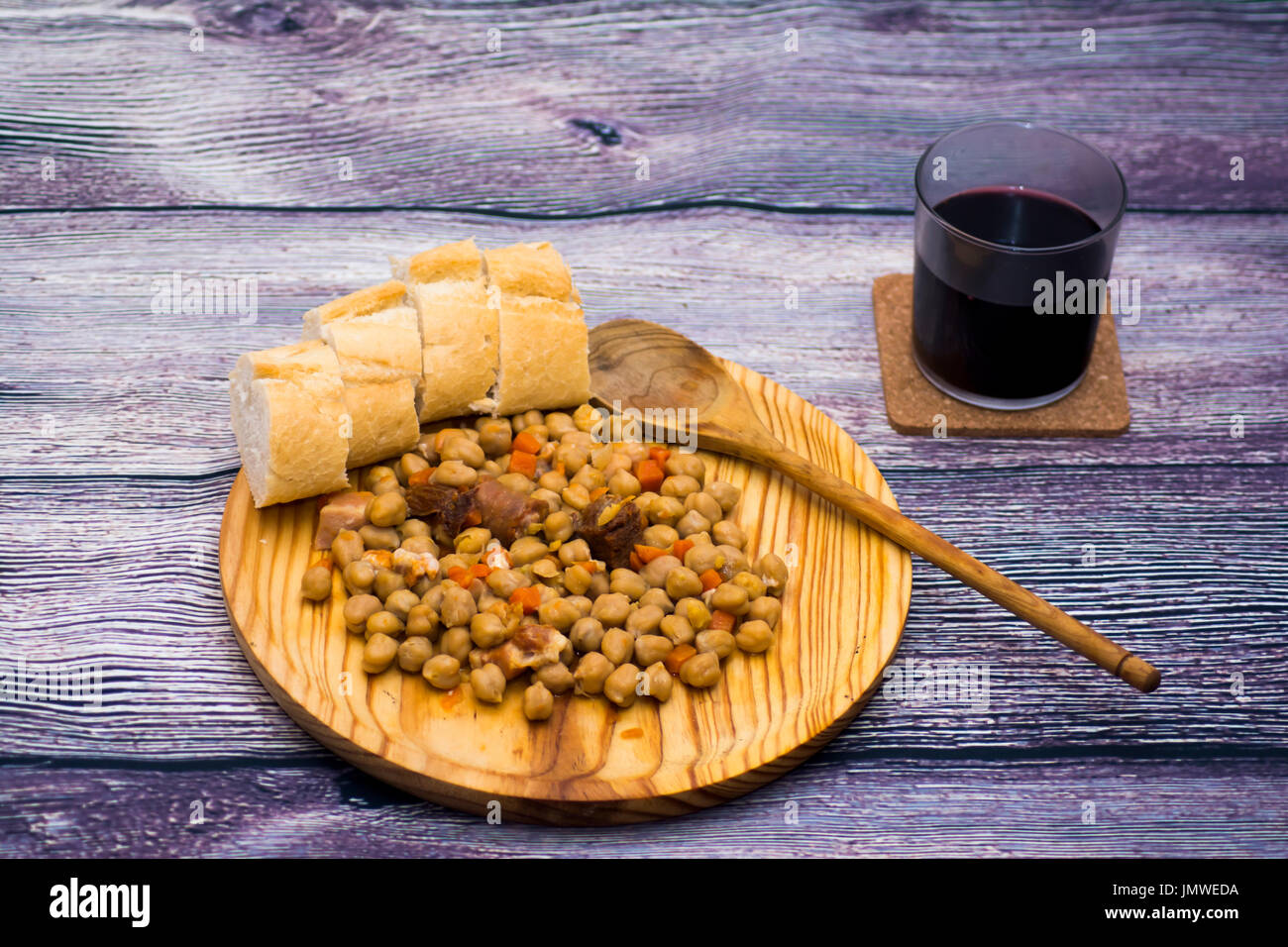 Madrid stew on a plate on a wooden table With bread and a glass of red ...