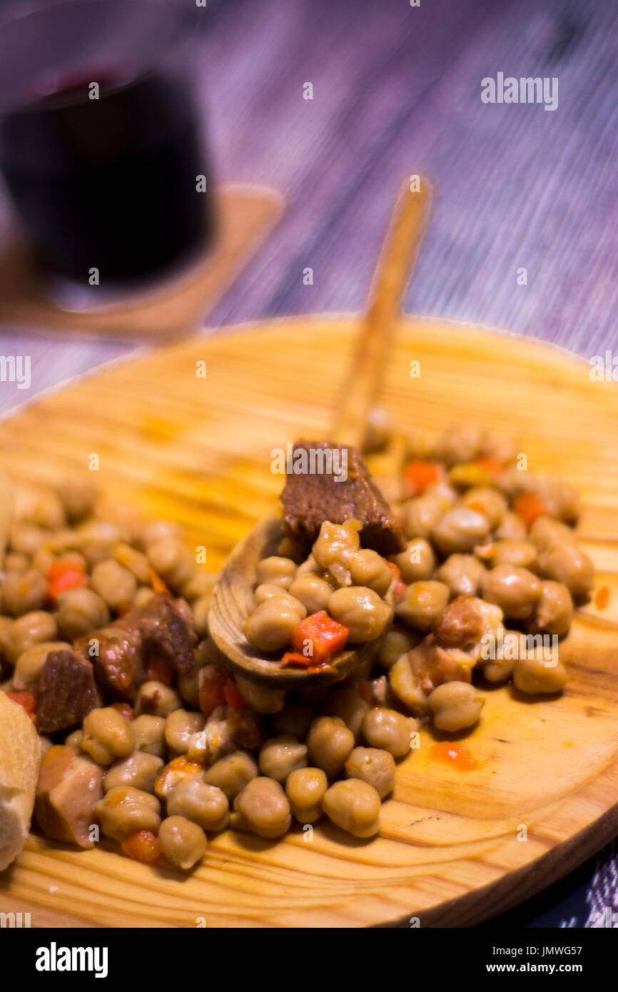 Madrid stew on a plate on a wooden table With a glass of red wine ...