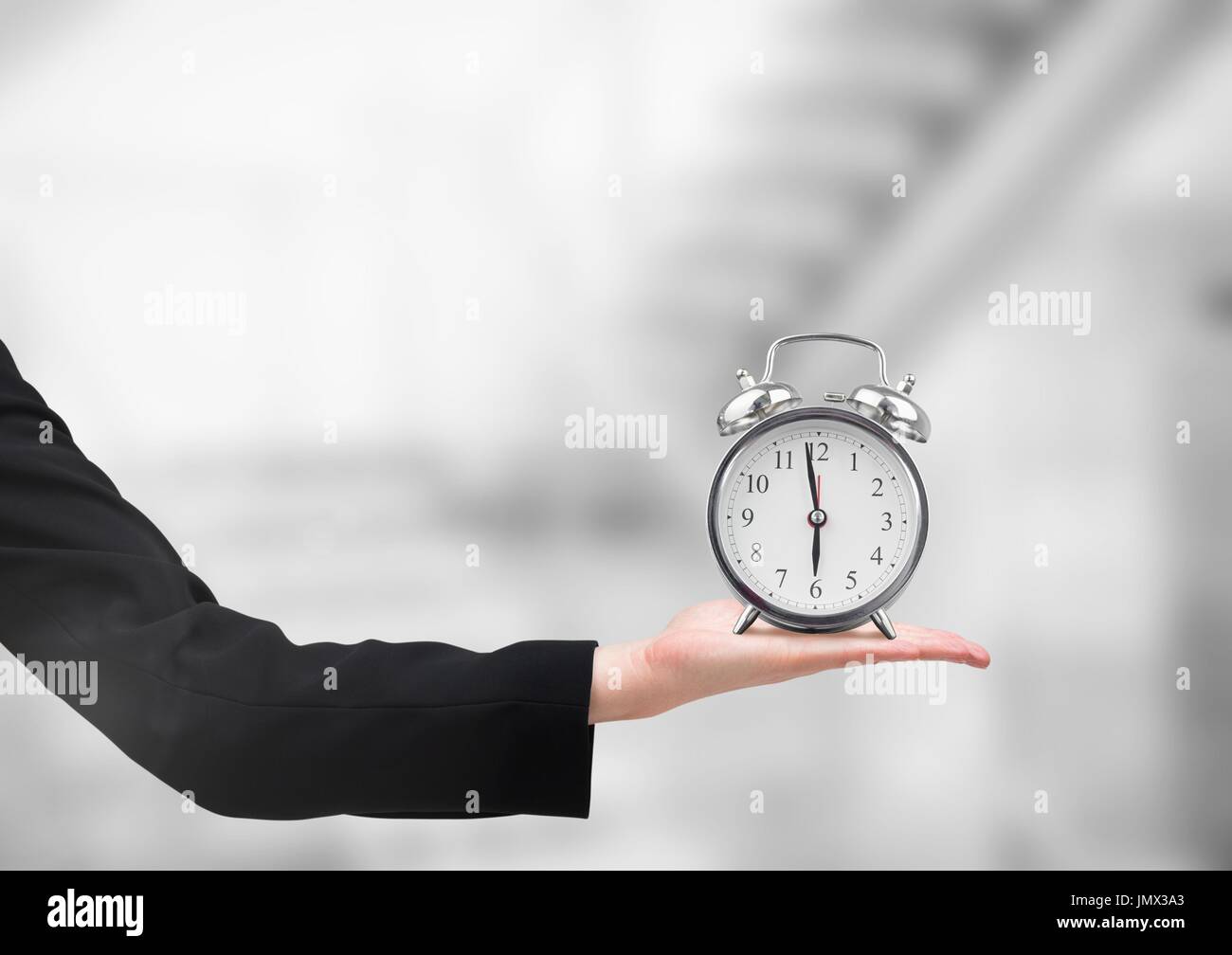 Digital composite of Arm holding clock with bright blurred background ...
