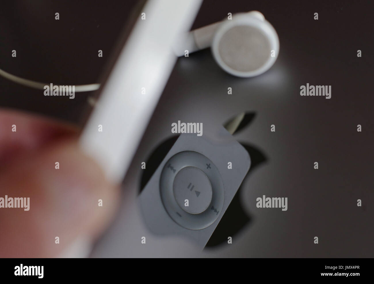 A 1st Generation iPod Shuffle music player reflected in an Apple logo ...