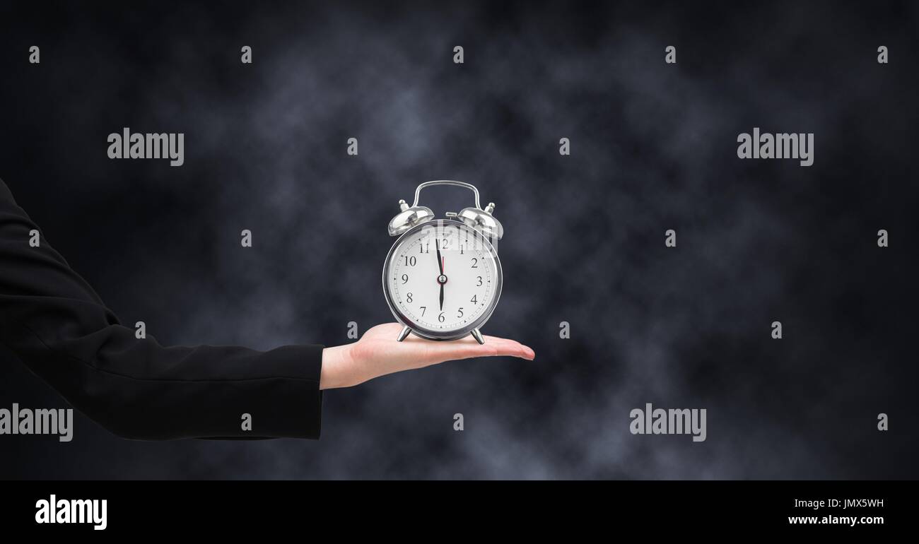 Digital composite of Arm holding clock in front of dark background ...