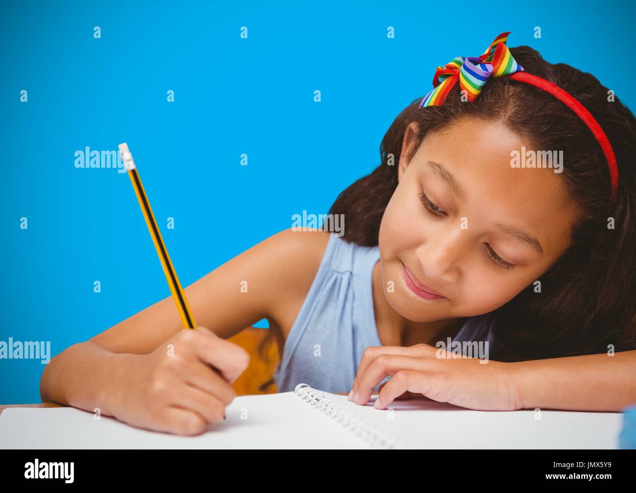 Digital composite of Girl writing in front of blue blank background ...