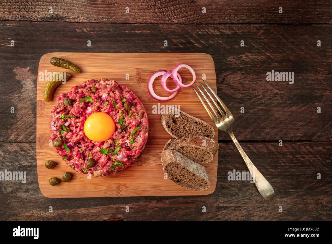 An overhead photo of a steak tartare with a raw egg yolk, rye bread ...