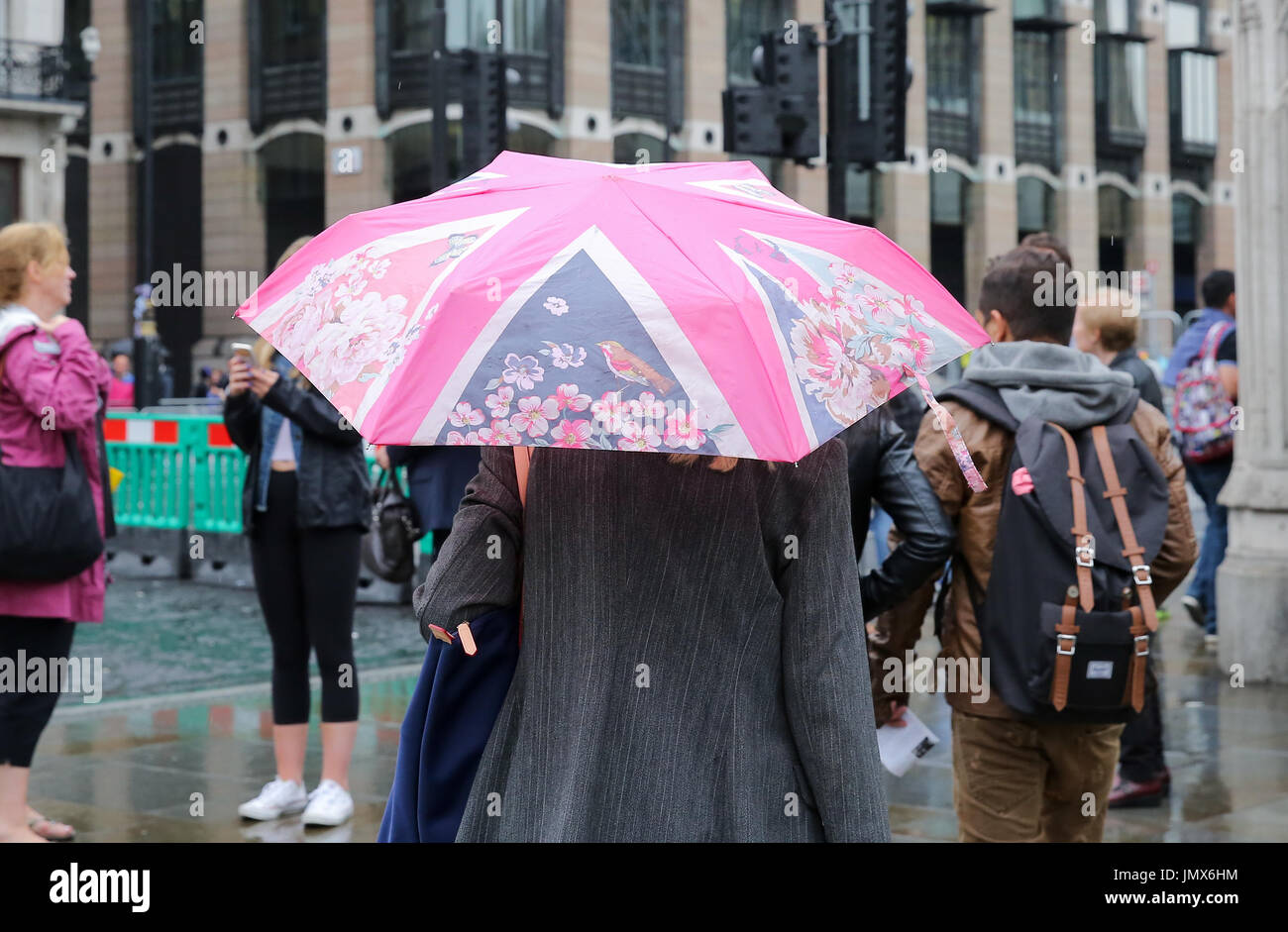 People take shelter from the rain under umbrellas in Westminster after ...