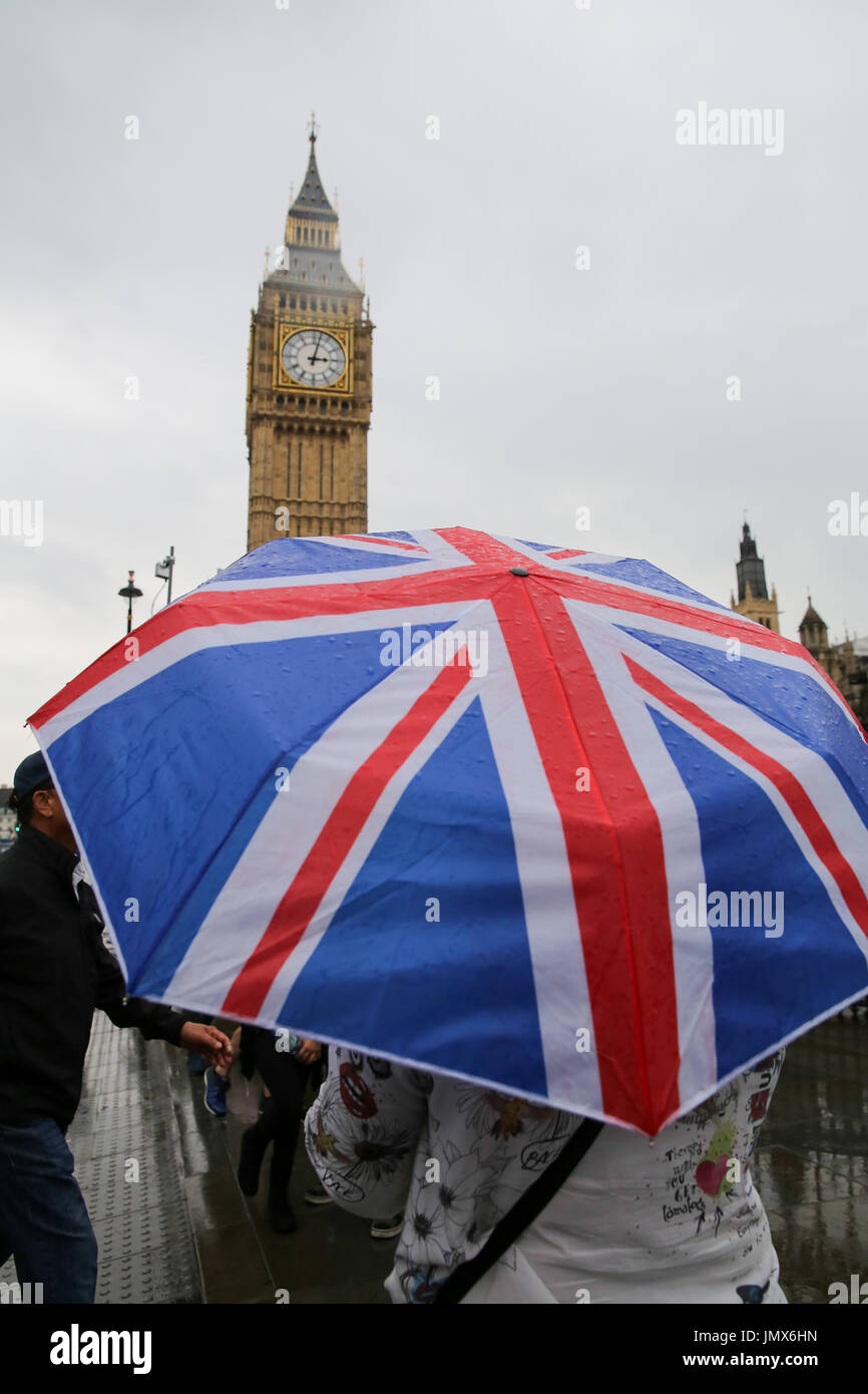 People take shelter from the rain under umbrellas in Westminster after ...