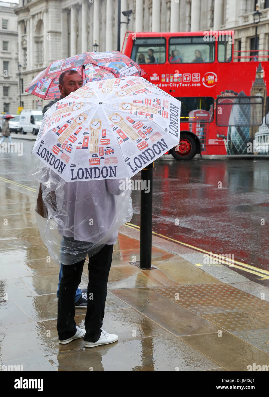 People take shelter from the rain under umbrellas in Westminster after ...