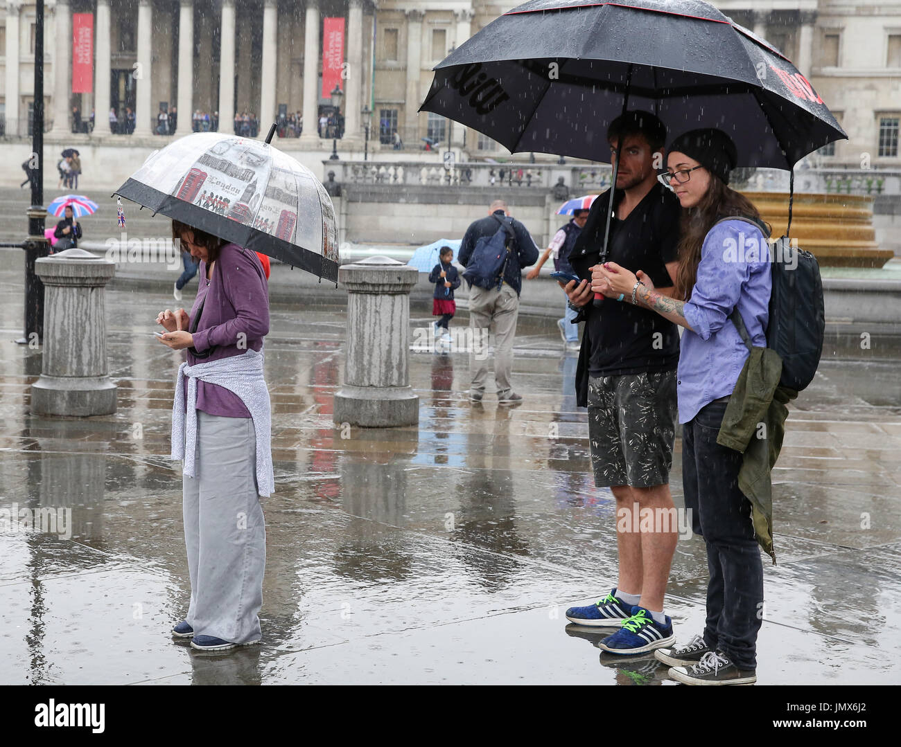 People take shelter from the rain under umbrellas in Westminster after ...