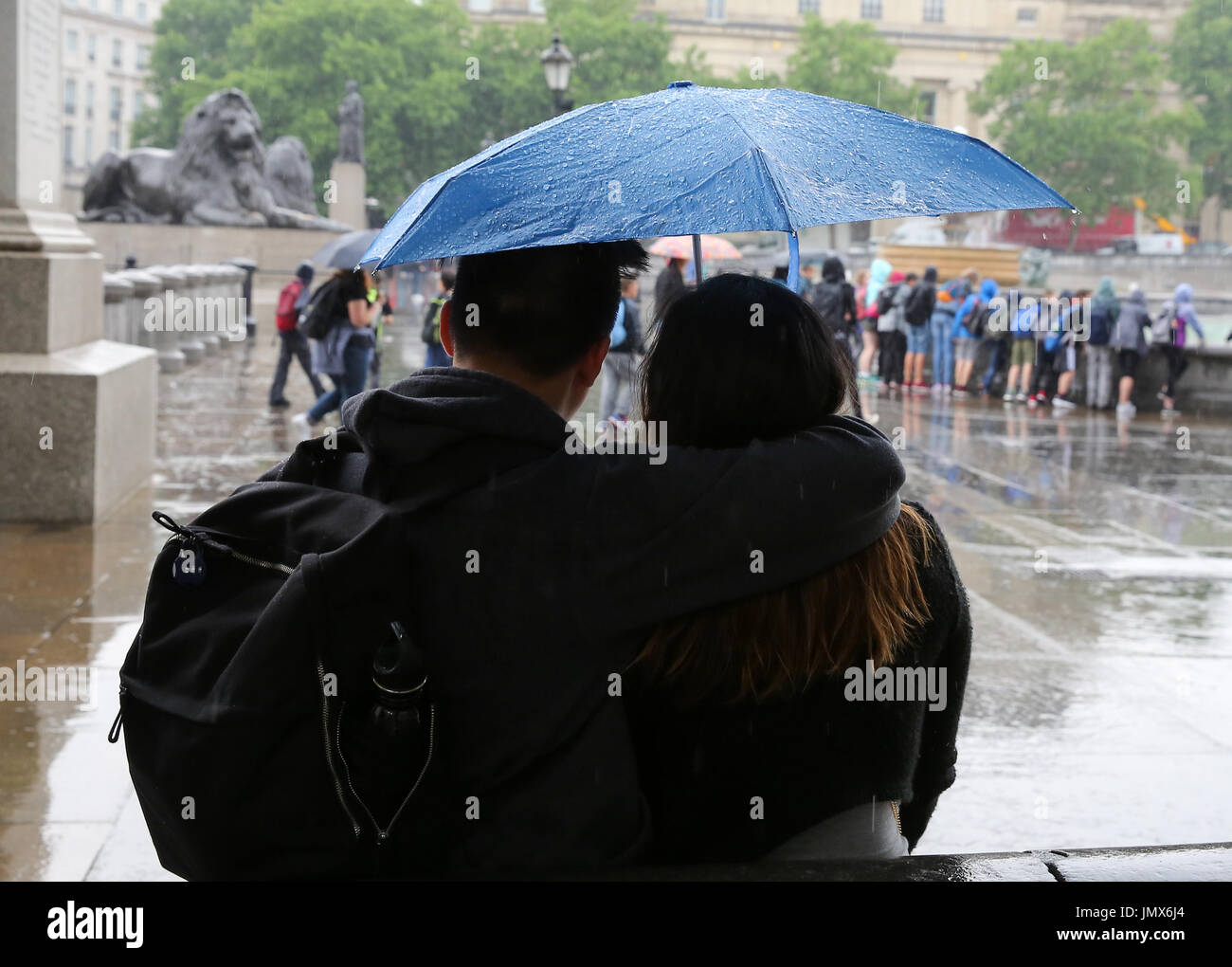 People take shelter from the rain under umbrellas in Westminster after ...