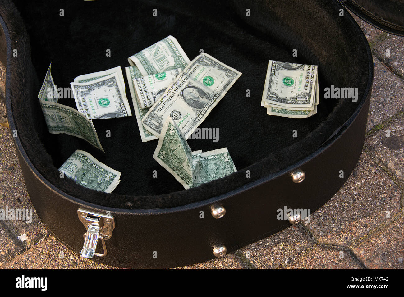 dollar bills as tip money in black guitar case on city sidewalk Stock ...