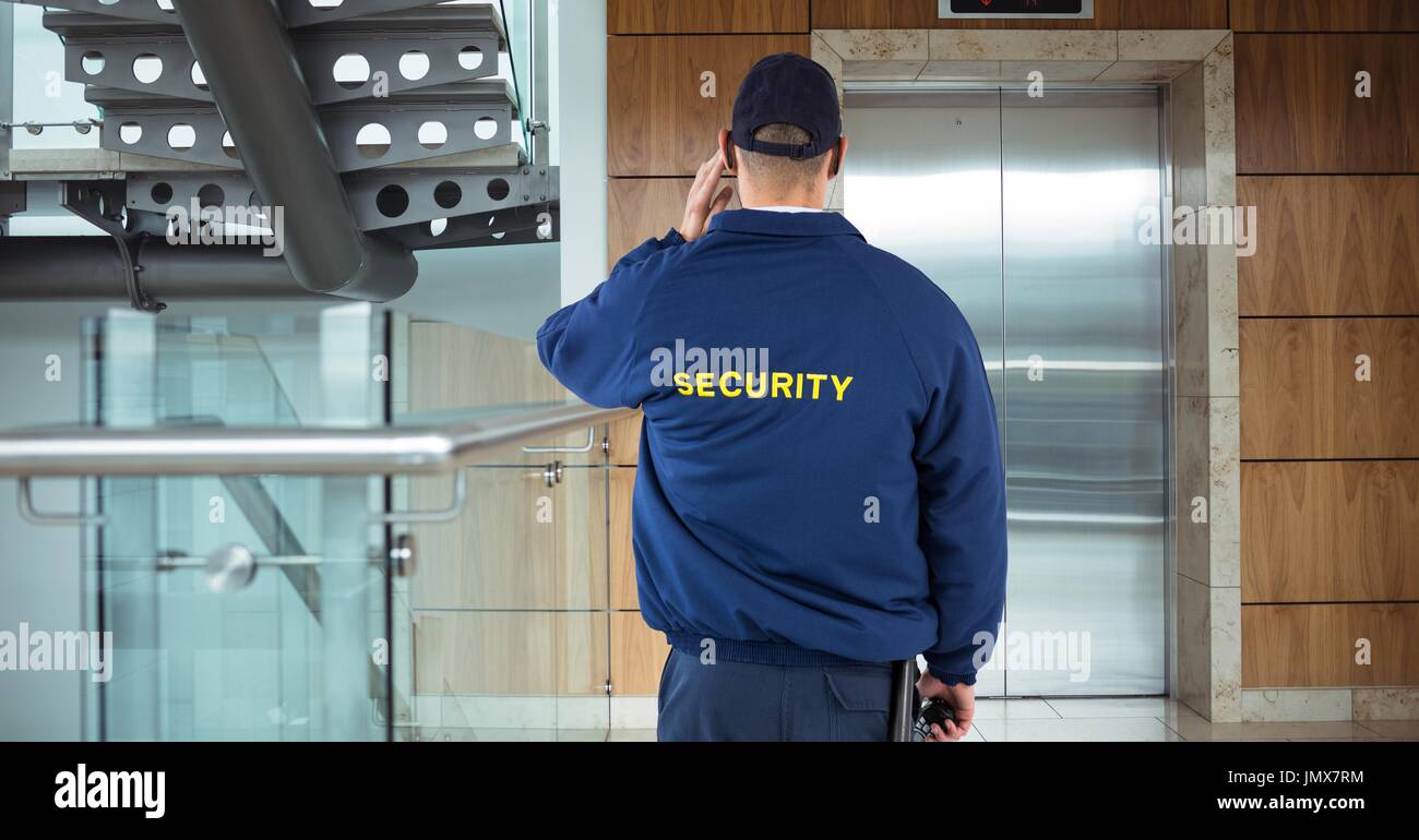 Digital composite of Rear view of security guard waiting for lift while ...