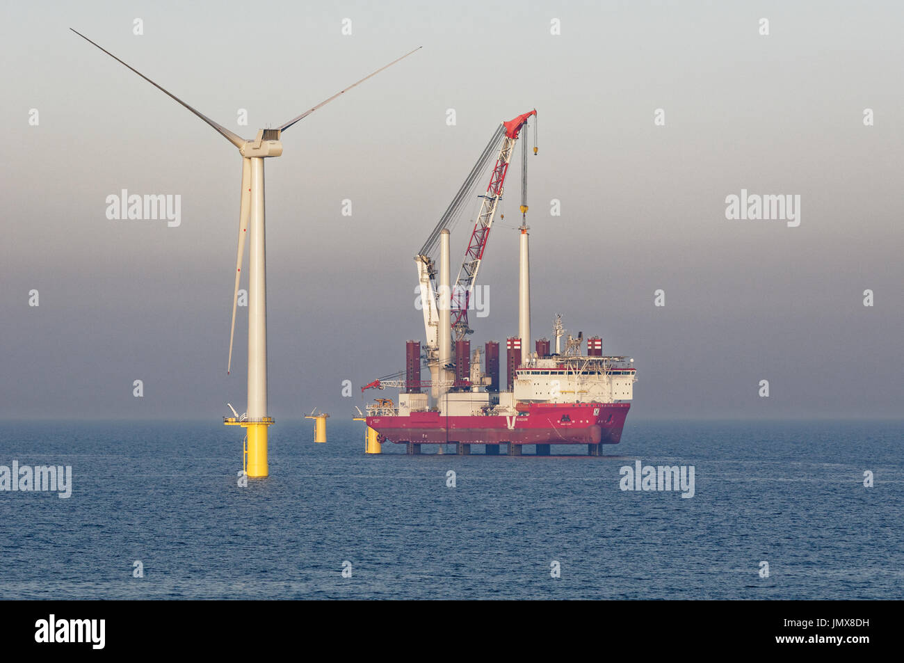 The jack-up crane vessel MPI Discovery lifts a wind turbine mast at the ...