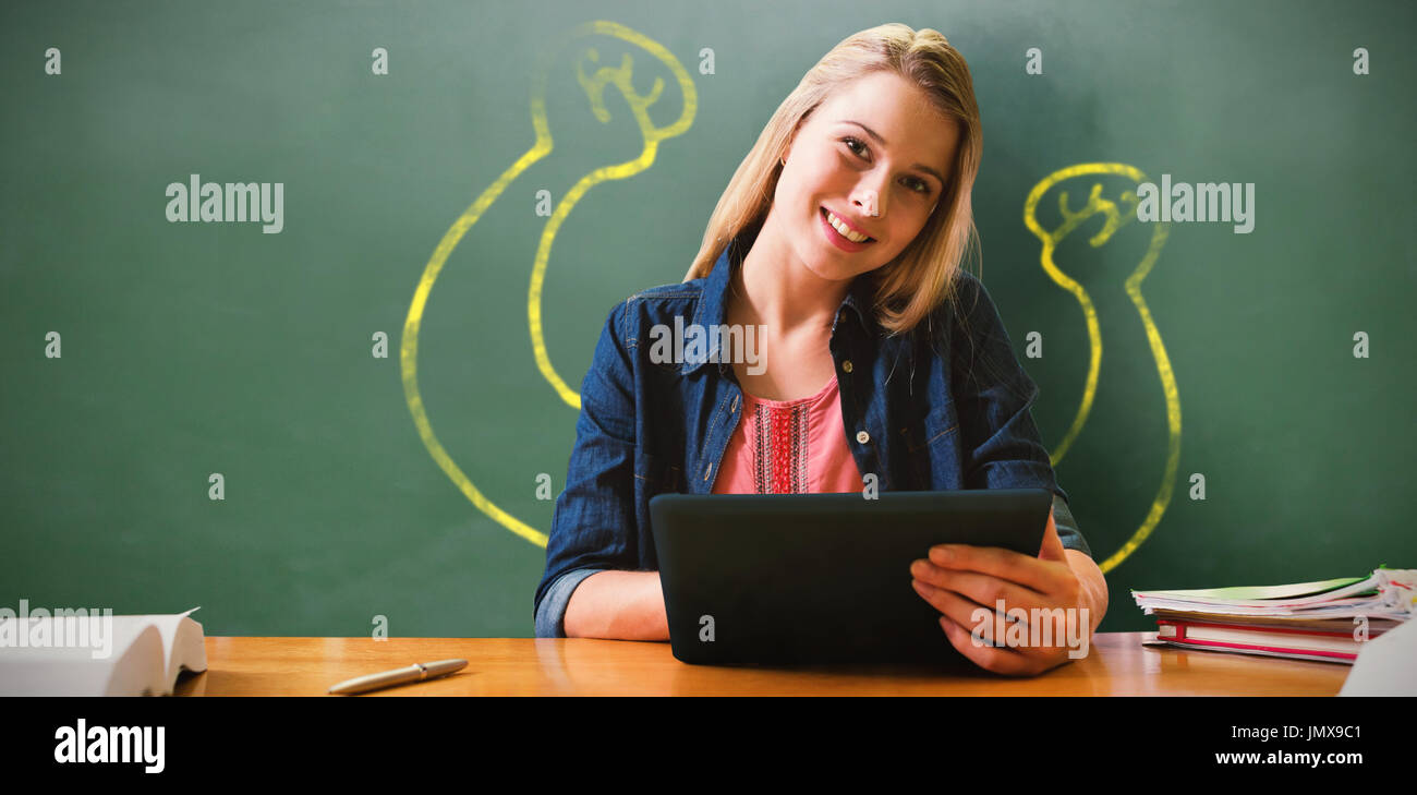 Student studying in the library with tablet against green chalkboard ...
